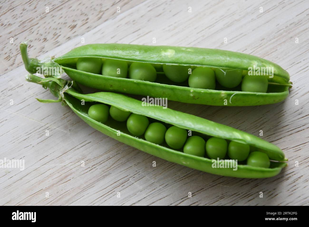 Two fresh garden pea pods (Pisum sativum), isolated on a wood ...