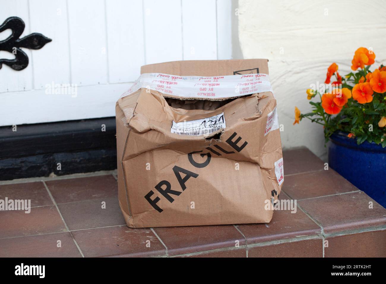 Damaged fragile parcel left on a doorstep by a courier Stock Photo - Alamy
