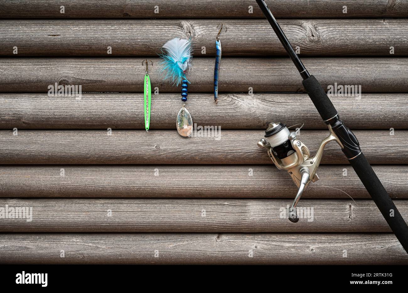 spinning wheel and rod with coourful lures hanging on a grey wall of ...