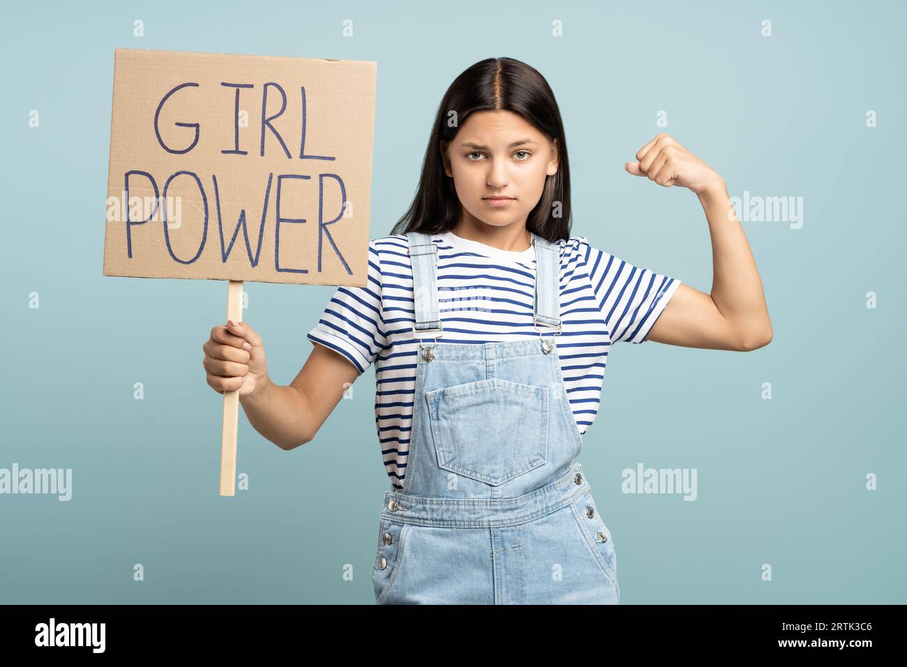 Teen girl showing power flexing arm holding girl power poster on blue ...