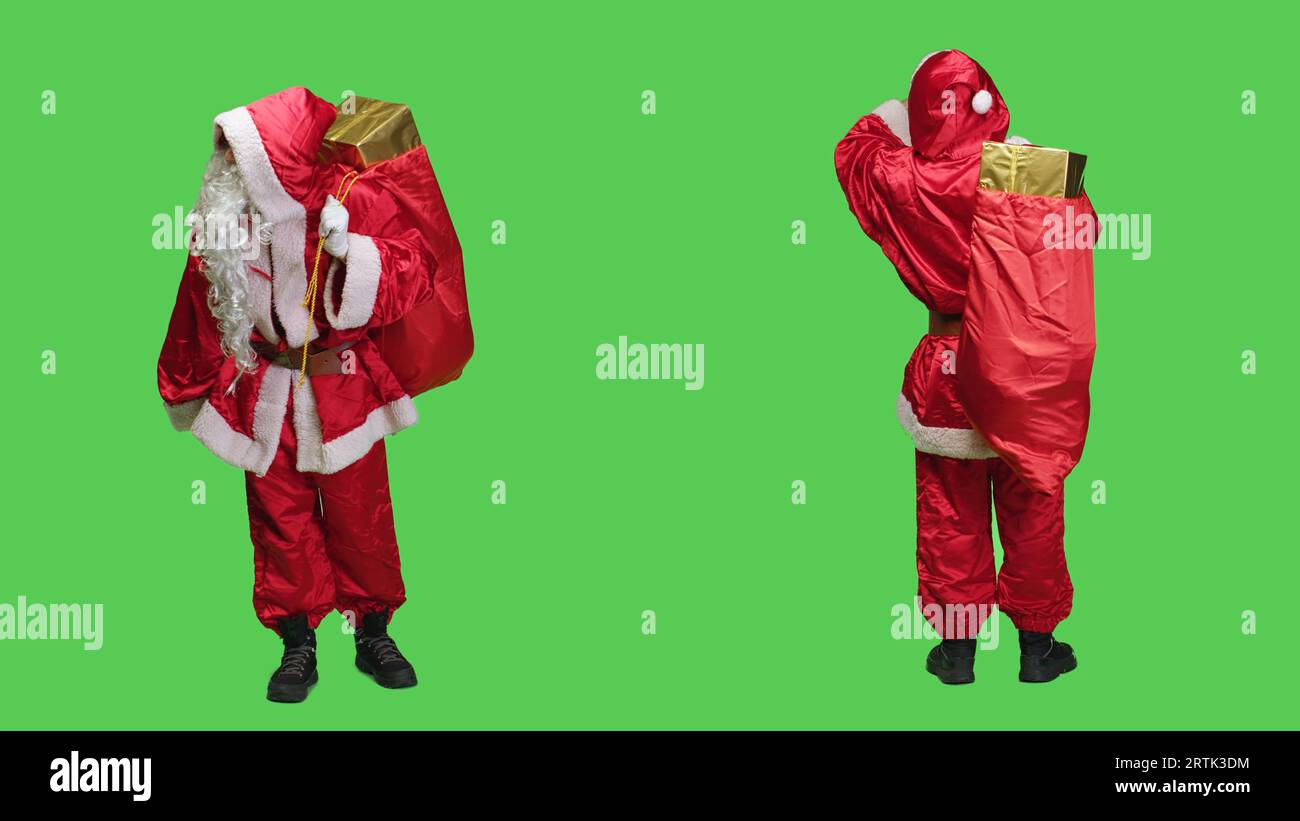 Father christmas looks around in studio, carrying big sack filled with ...