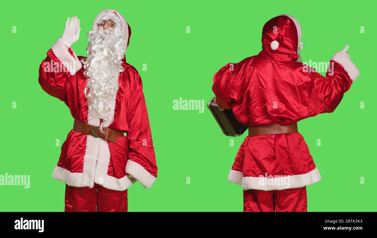 Man in santa claus suit waving hello and hitchhiking with suitcase ...