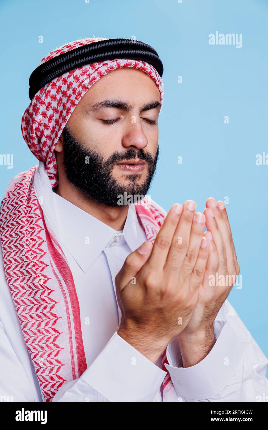 Religious muslim man with closed eyes praying to god with open arms ...
