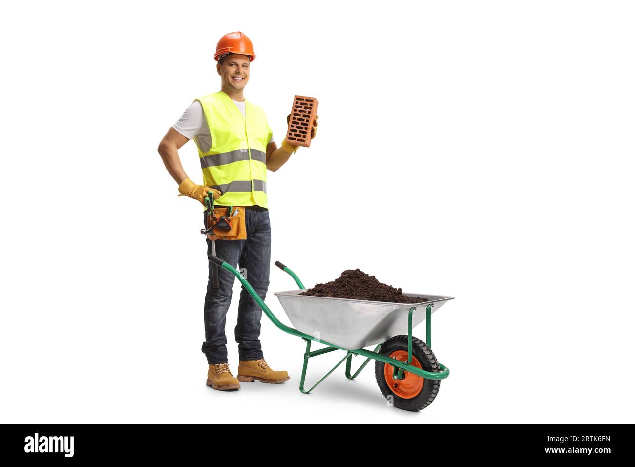 Construction worker holding a brick and standing behind a wheelbarrow ...