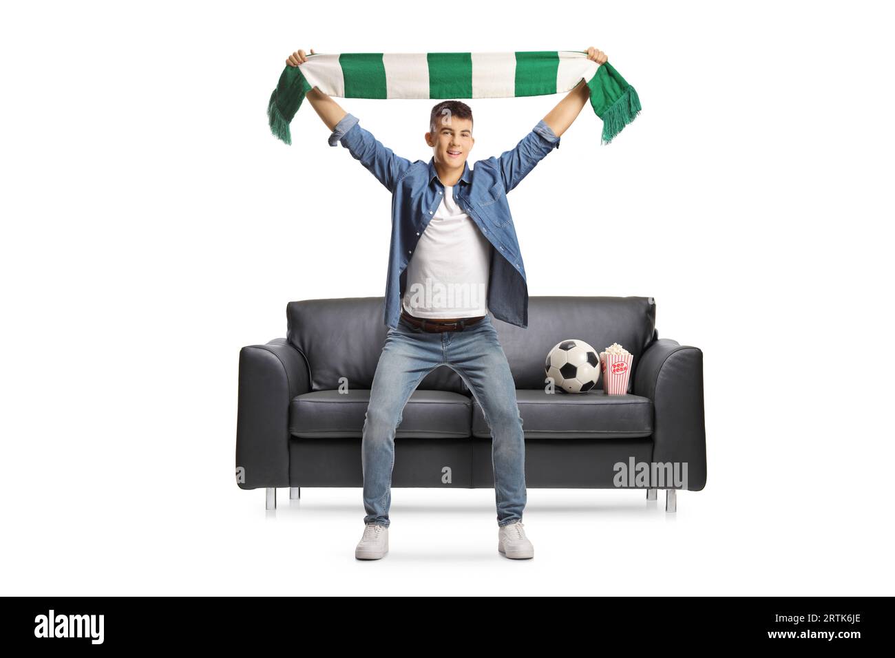 Happy young man cheering with a scarf in front of a couch isolated on ...