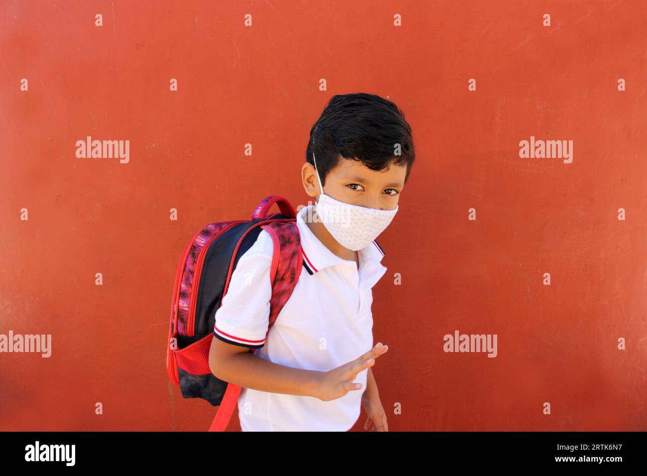Latino boy with uniform shirt, backpack and mask back to school happy ...