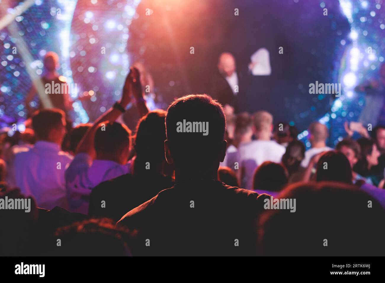 A crowded concert hall arena with scene stage lights with musicians ...