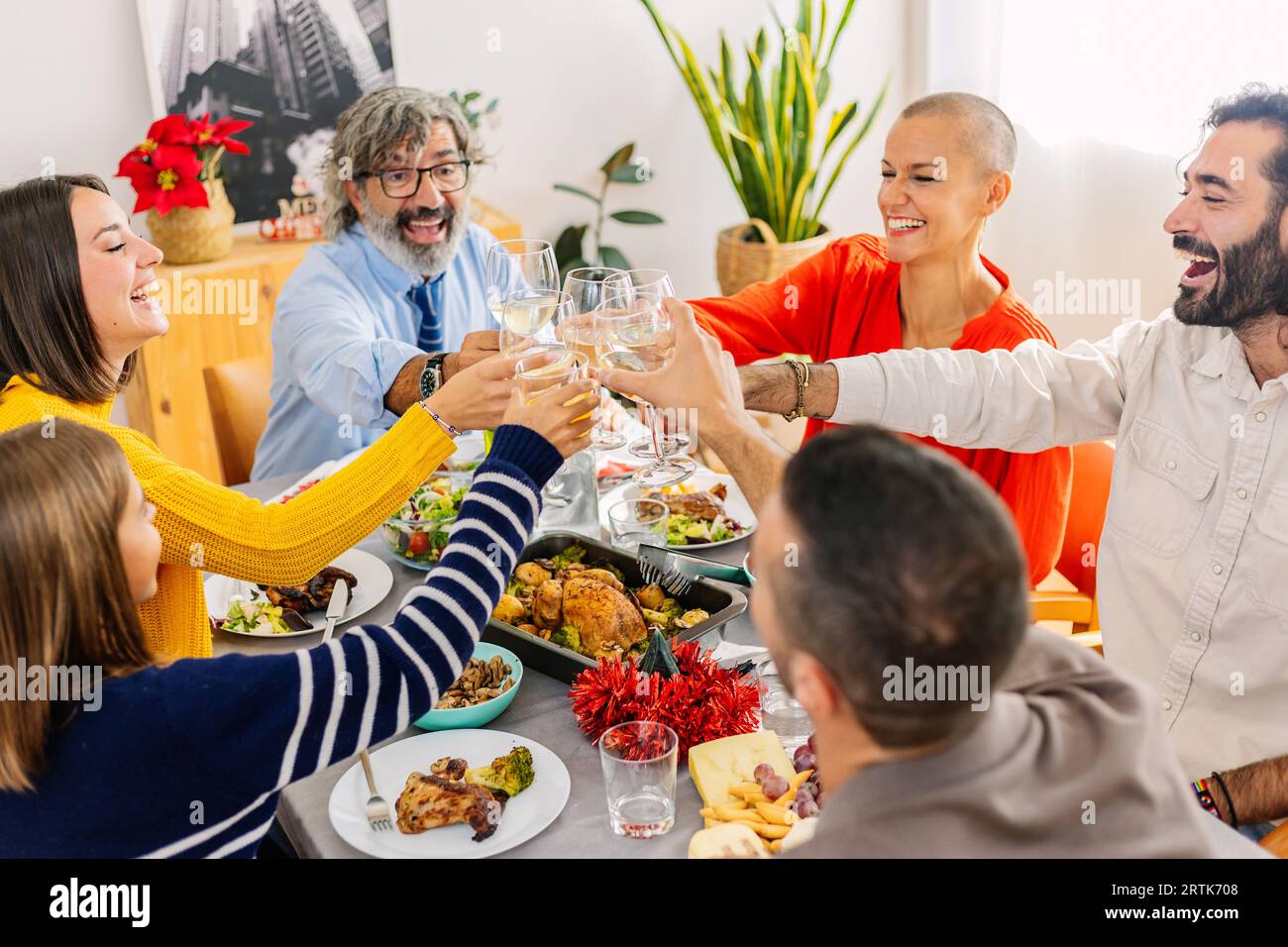 Happy multi generational family toasting white wine at home party ...
