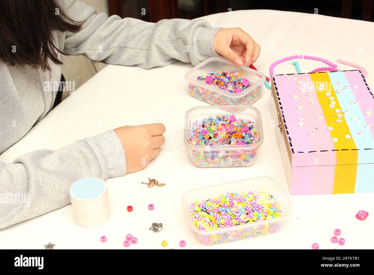 Teenage woman's hands make friendship bracelets to distribute and ...