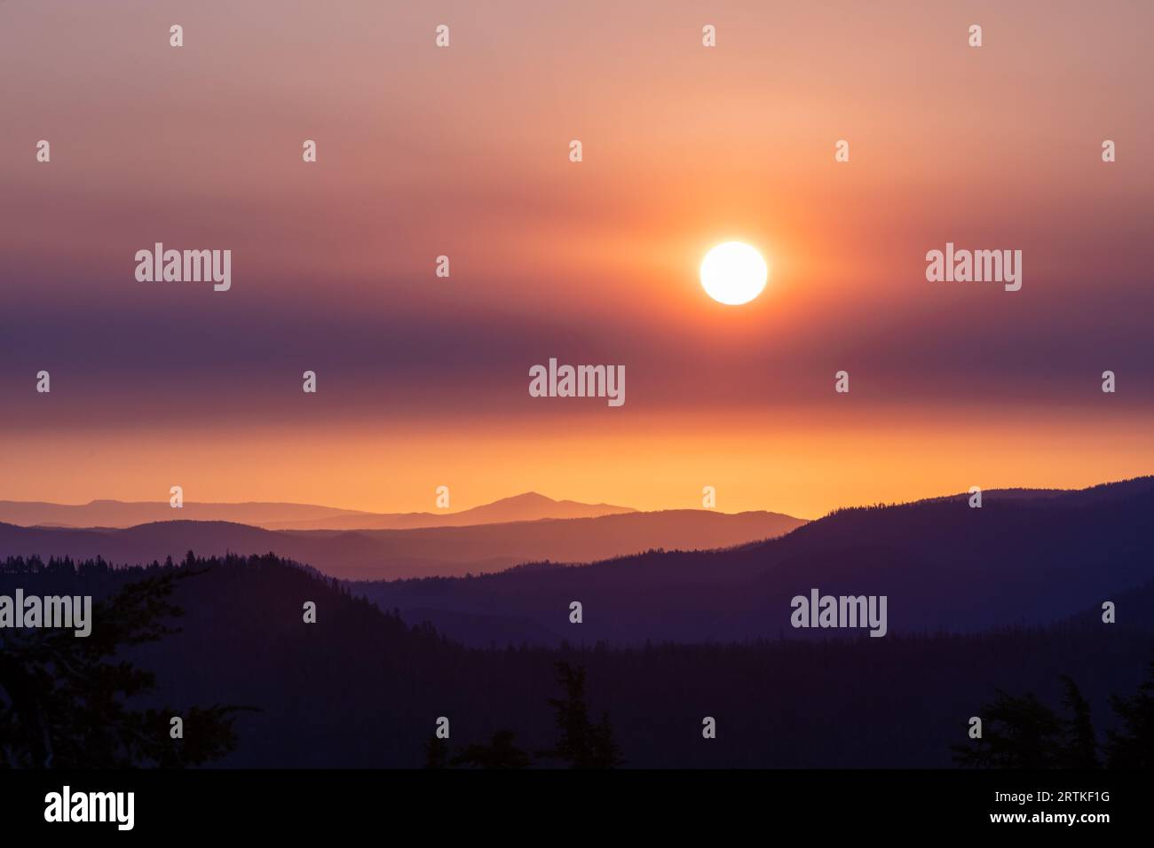 Colorful Layers of Clouds and Forest Below Dimmed Sun In The Clouds in ...
