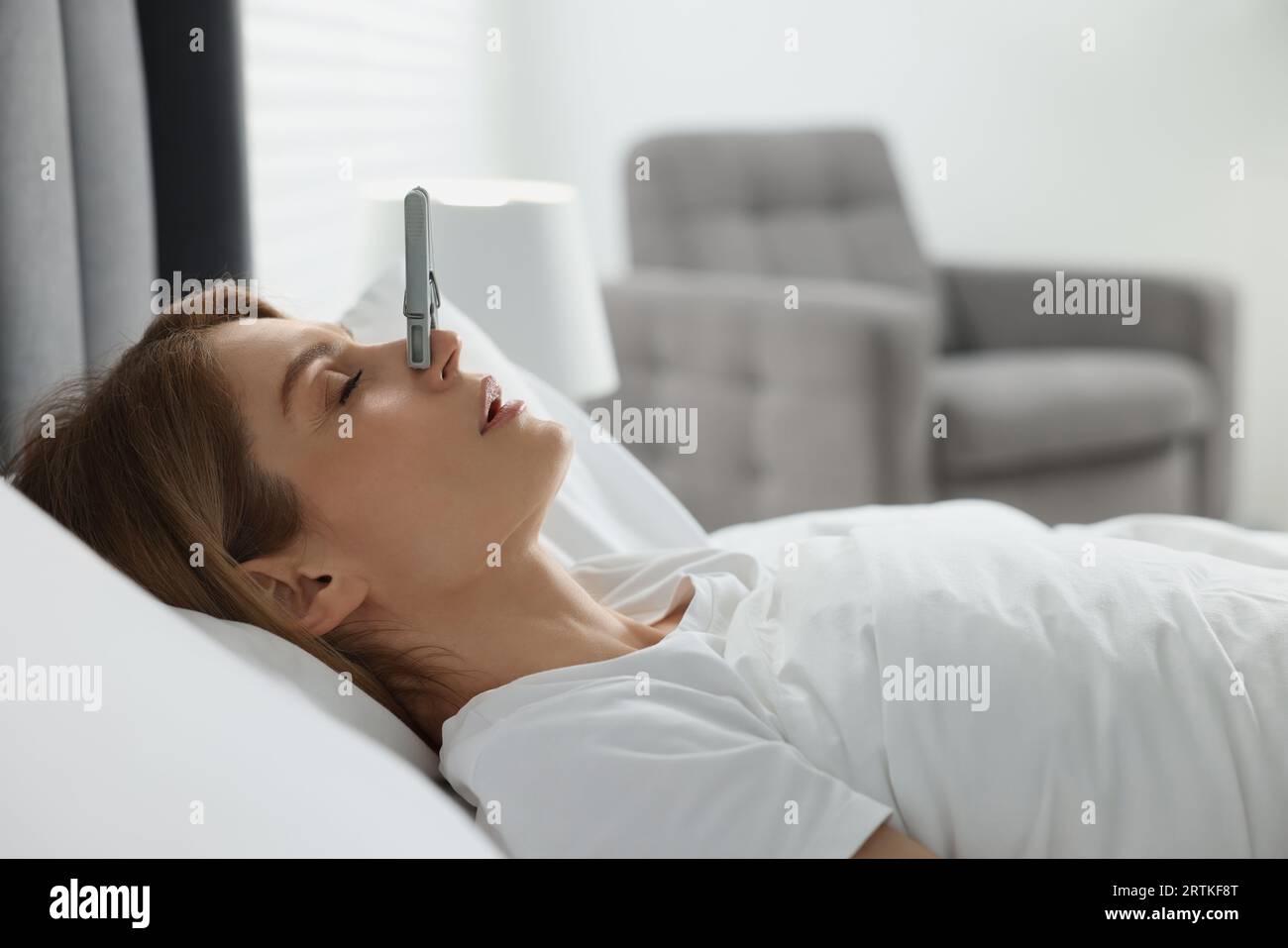 Woman sleeping with clothespin on her nose in bed at home. Problem with ...