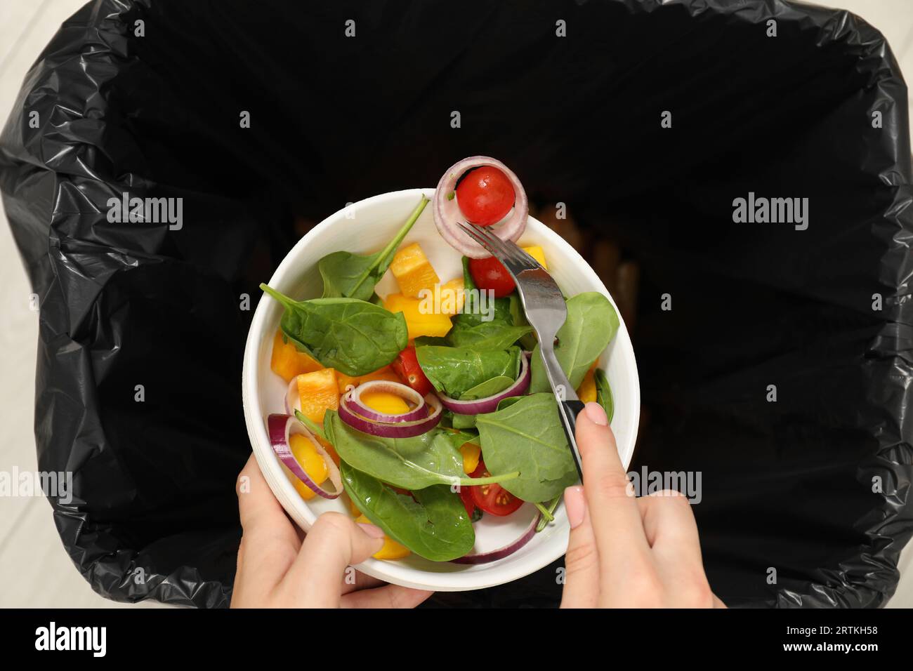 Woman throwing vegetable salad into bin indoors, top view Stock Photo ...