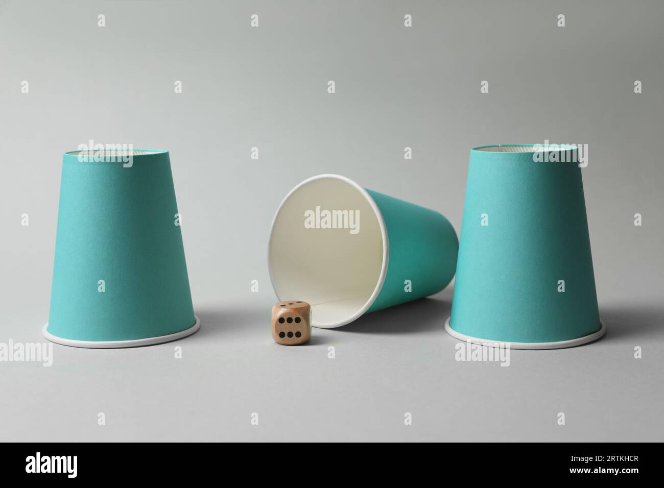 Three paper cups and dice on light grey background. Thimblerig game ...