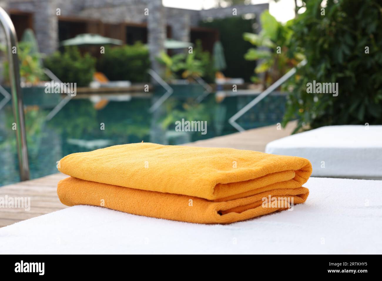 Beach towels on sun lounger near outdoor swimming pool. Luxury resort ...