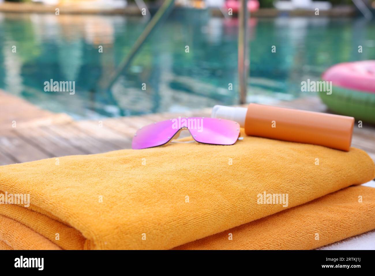 Beach towels, sunglasses and sunscreen on sun lounger near outdoor ...