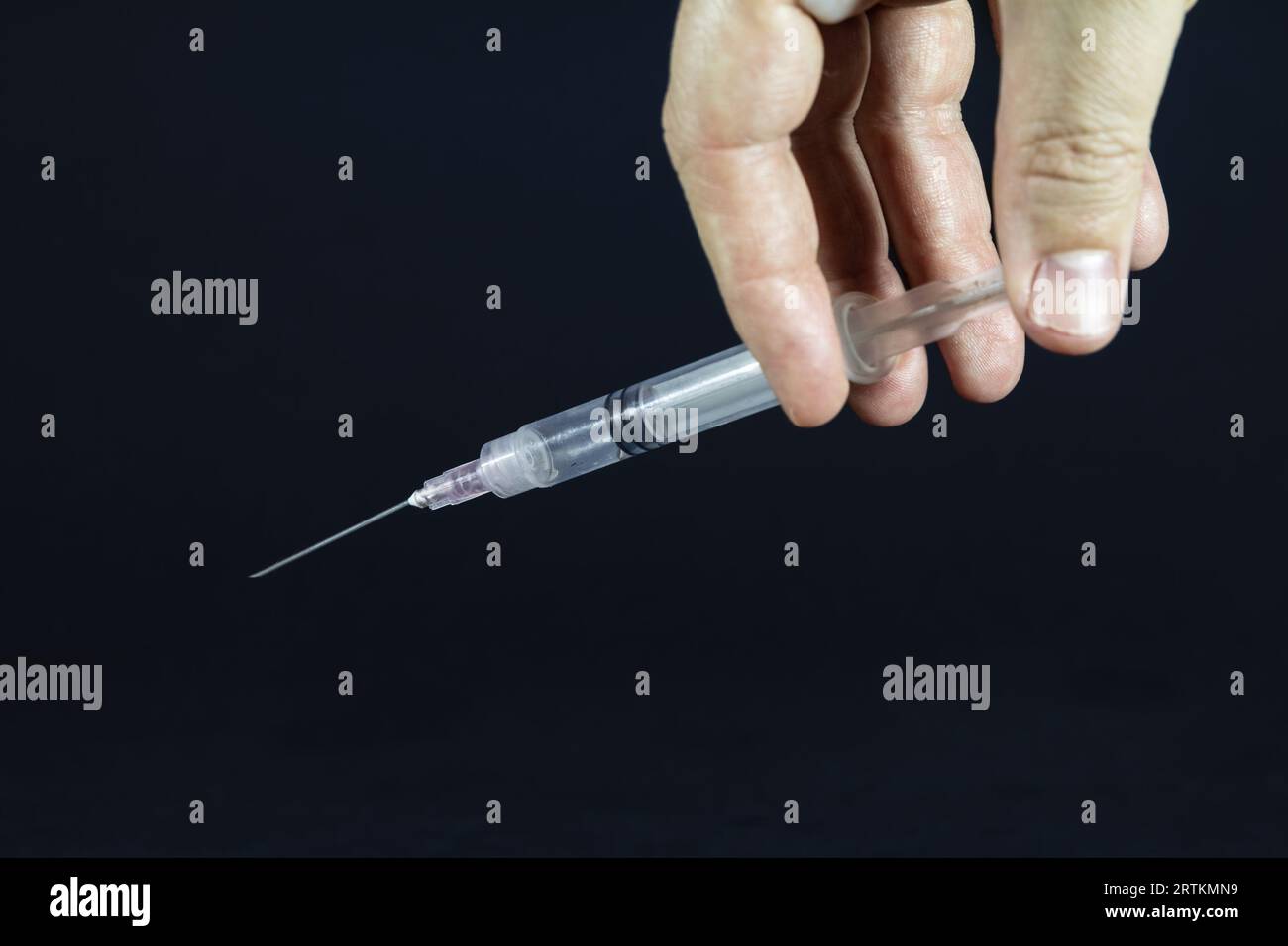 Picture of a syringe isolated on a black background, held by a hand, ready to inject drug Stock ...