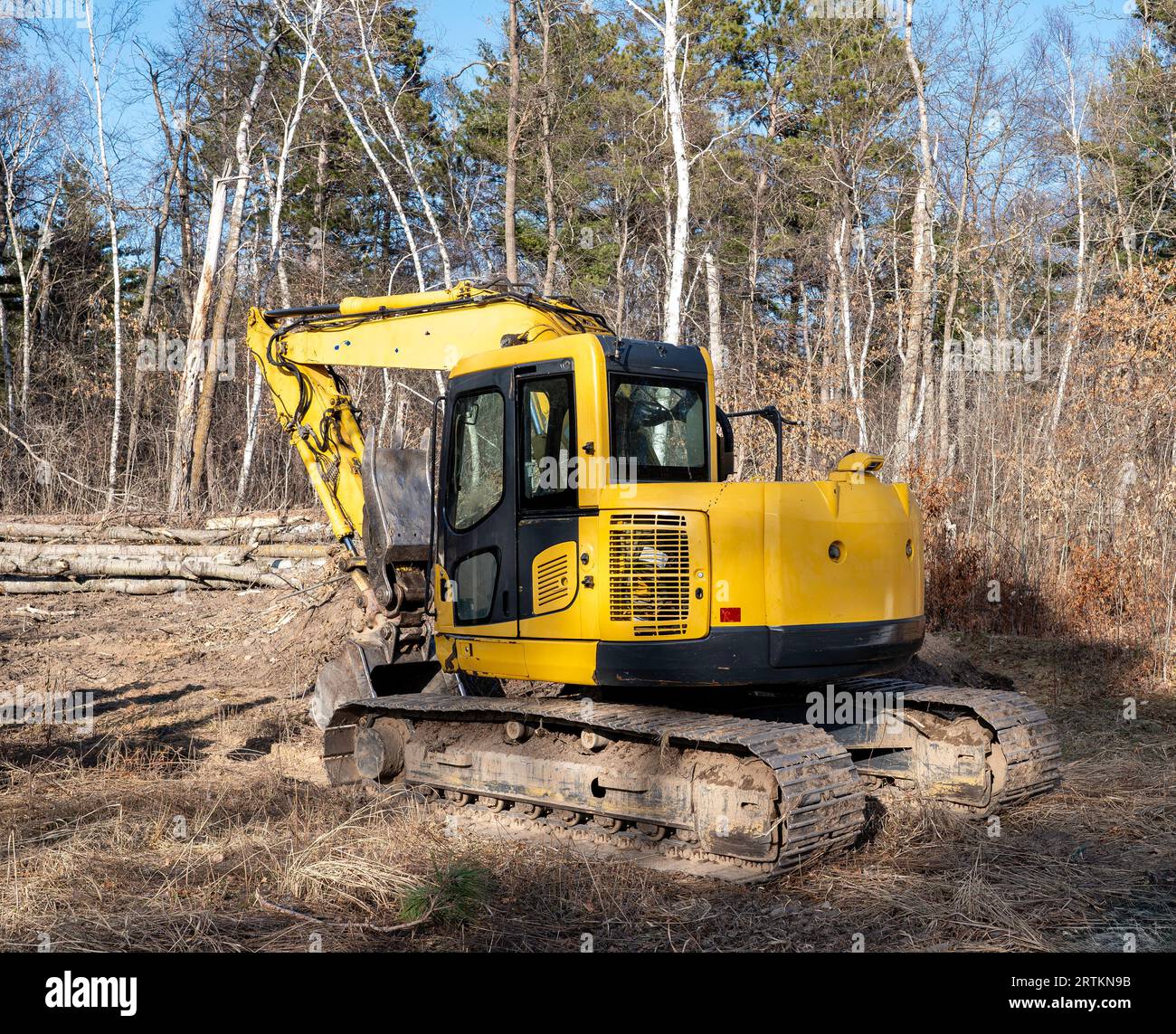 Yellow excavator machine with digging bucket and tracks is parked near ...