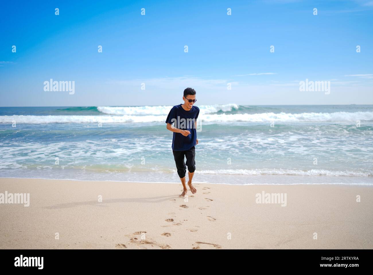 a man in a blue shirt, being chased by the waves. This beach looks ...