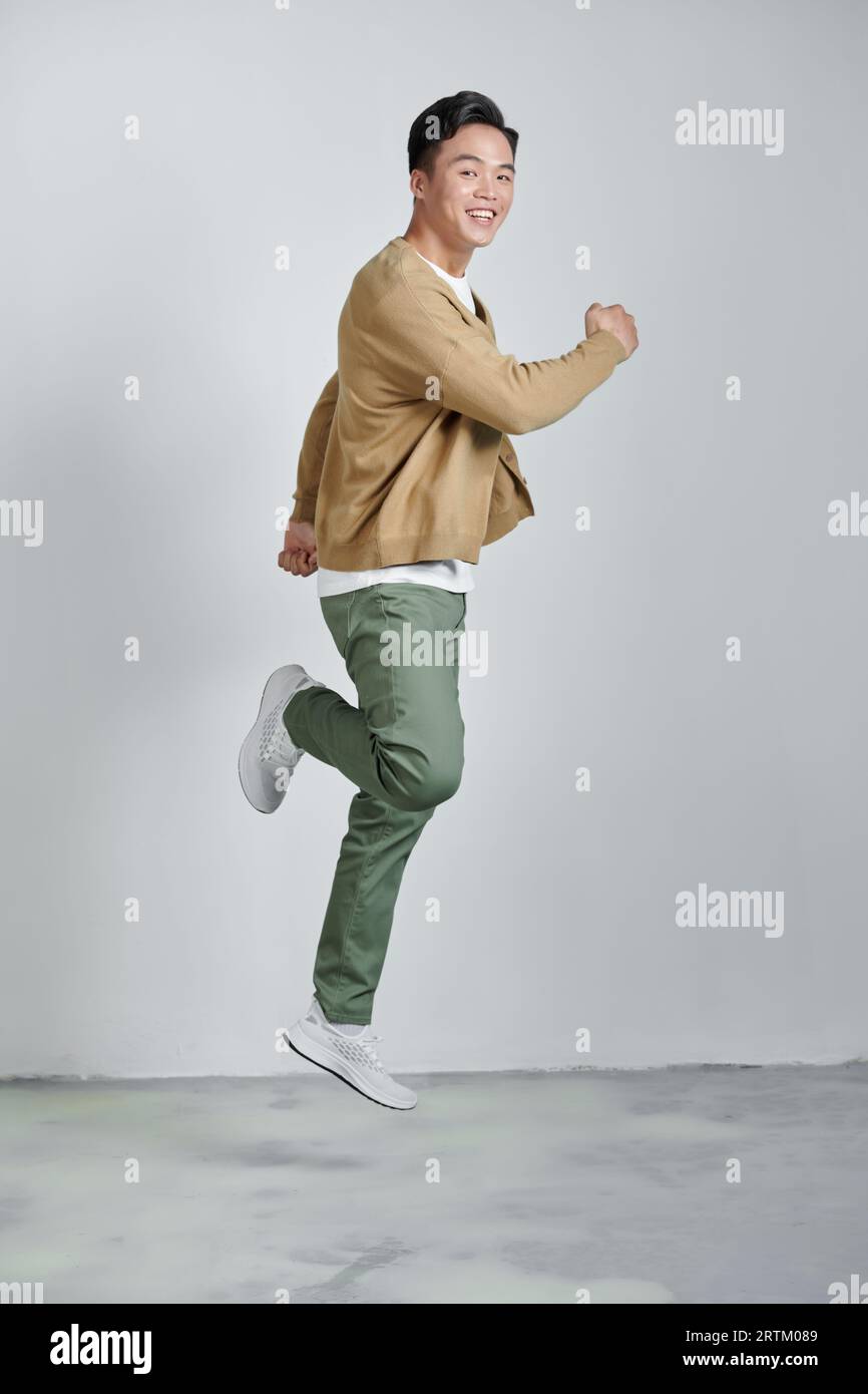 Full length Asian man running jumping in air gesture with happy smile ...