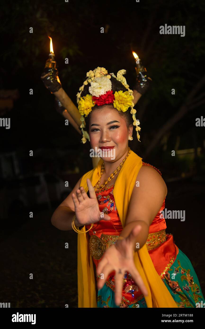a traditional Javanese dancer dances with colorful flowers on her fist ...