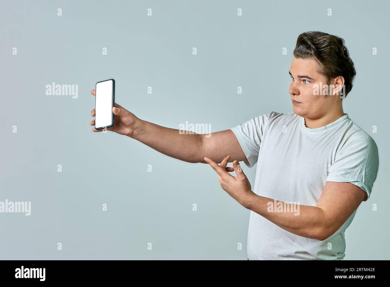 A man at arm's length shows a phone screen on a gray background, mockup ...