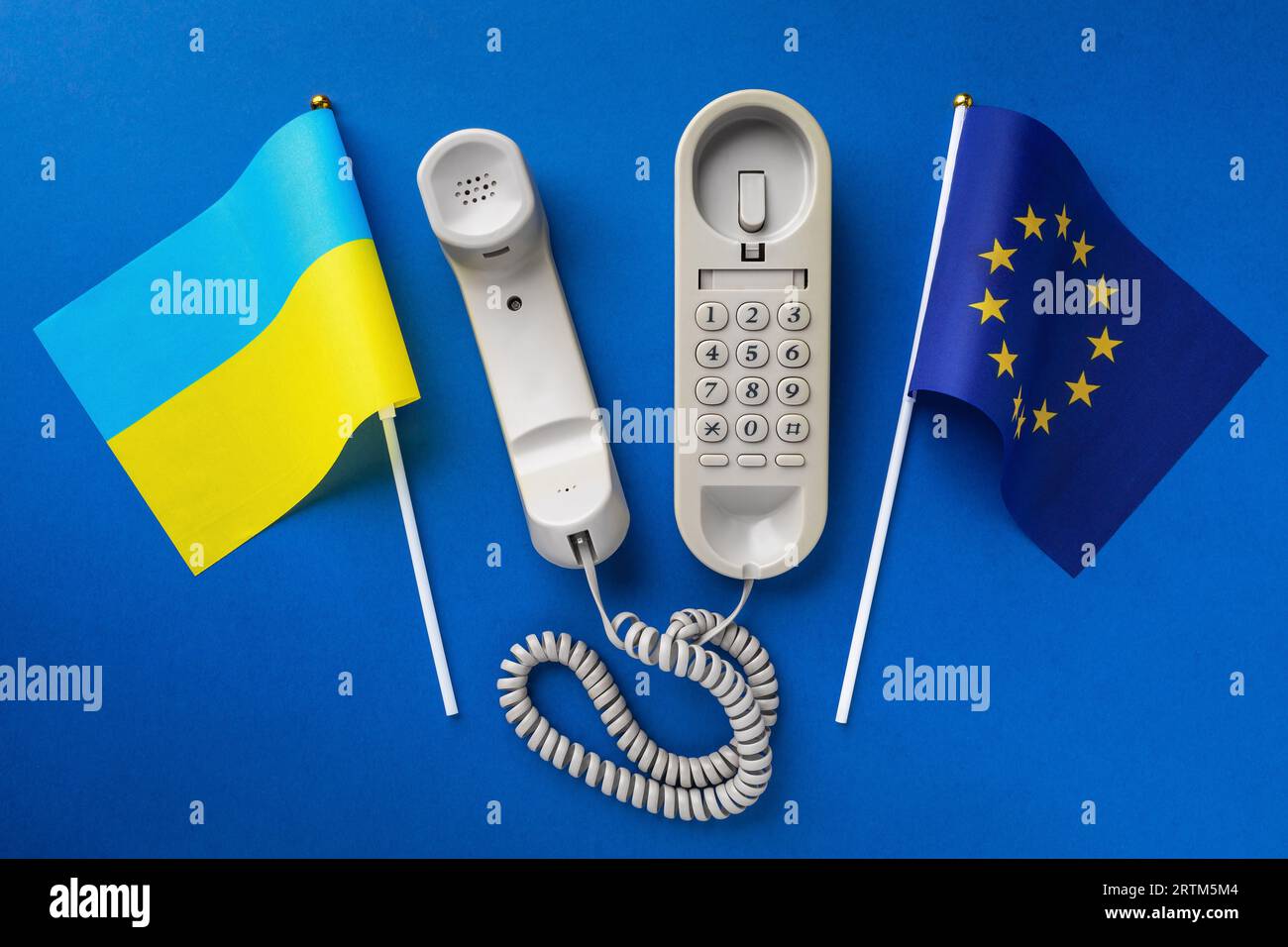 Top view of an old telephone and two flags on a blue background ...