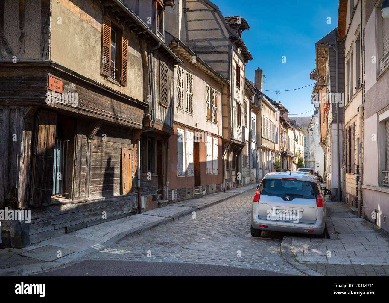A car parked on a small cobbled street lined with traditional ancient ...
