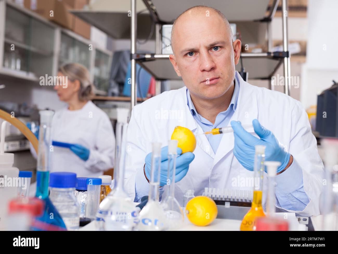 Biochemist injecting chemicals into lemon Stock Photo - Alamy