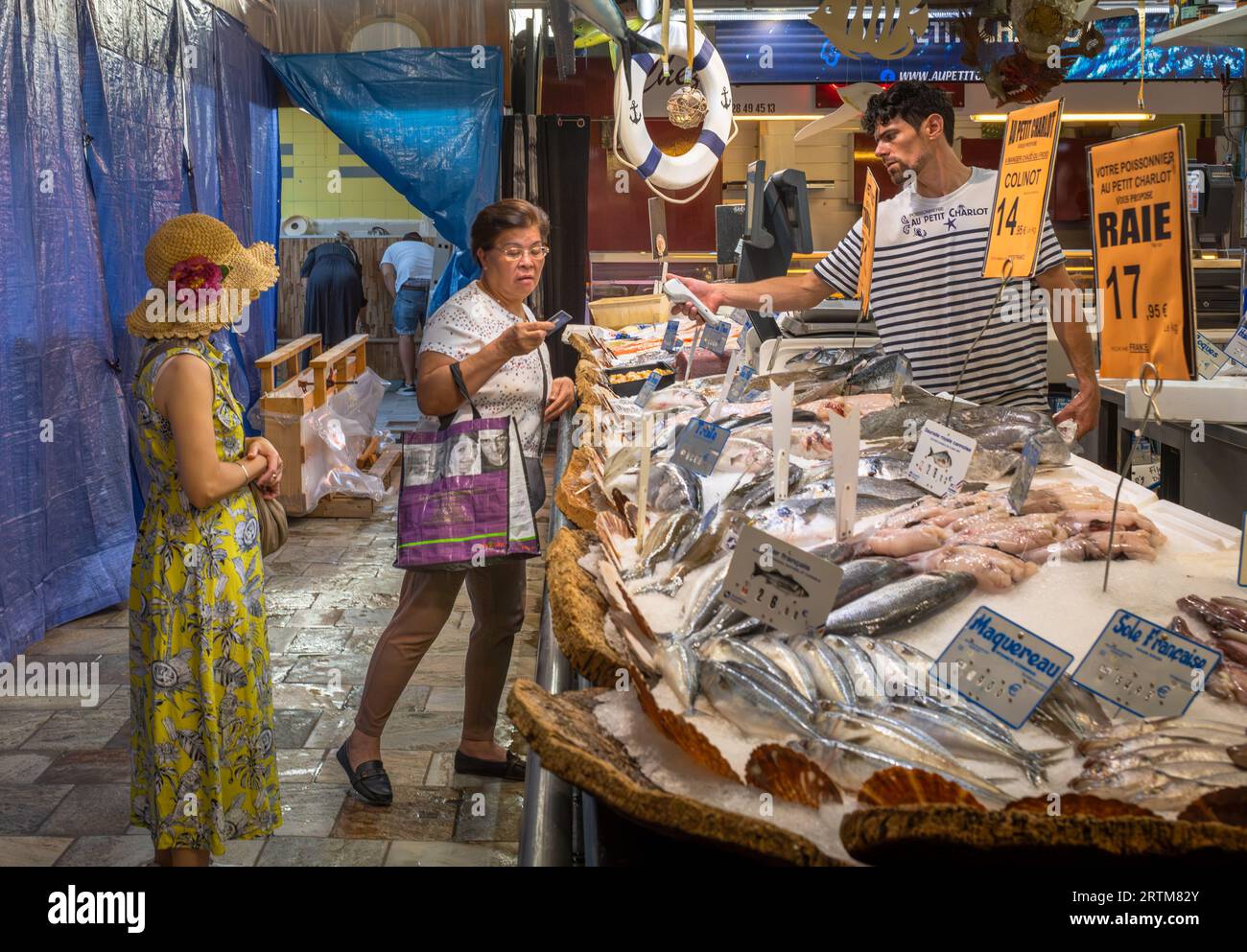 An Asian women pays by credit card as she buys fish from a fishmonger ...