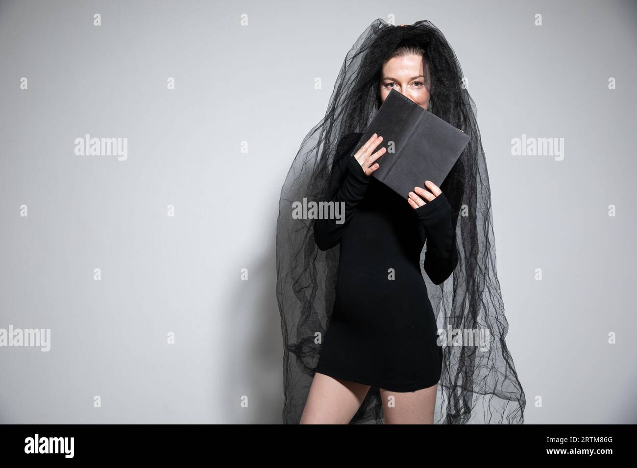black bride witch witch with a book at her face Stock Photo - Alamy