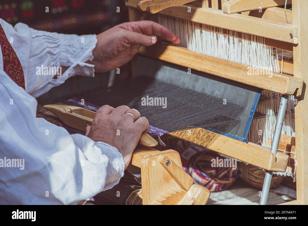 A craftswoman working on an ancient wooden weaving loom in traditional ...