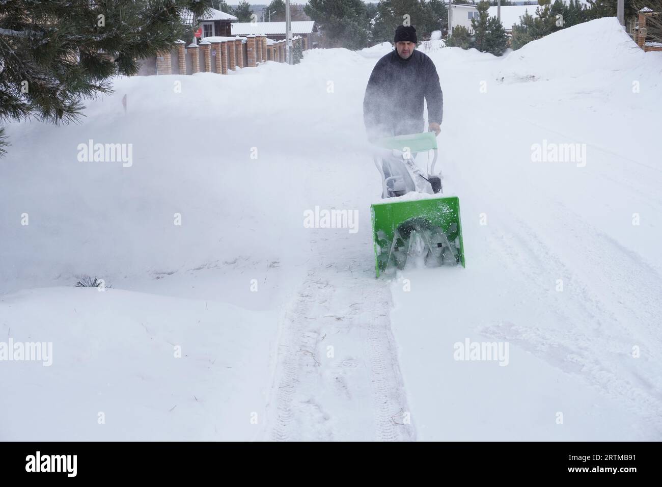 A man cleans snow in the winter in the courtyard of the house, man ...