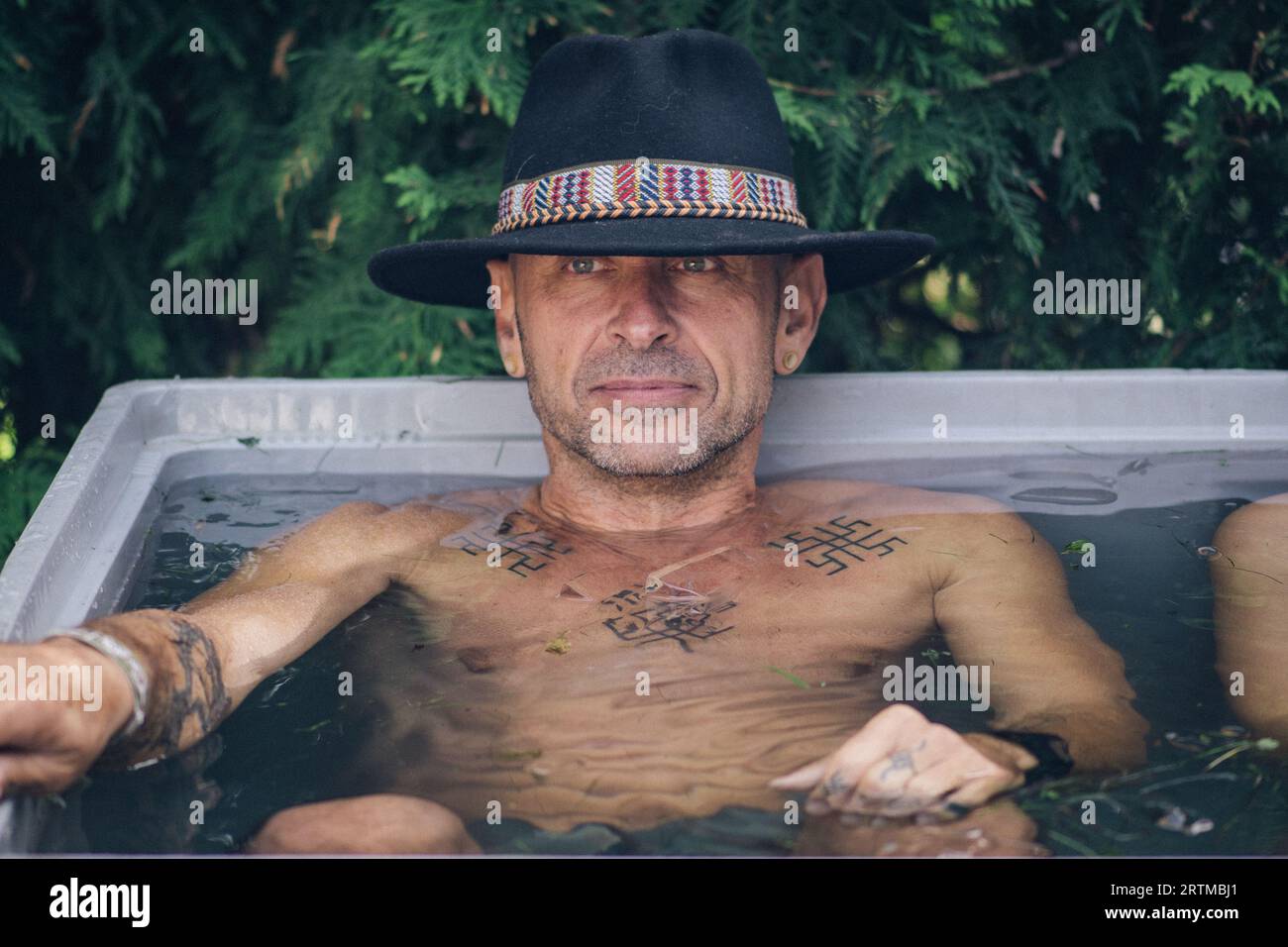 Man ice bathing in the cold water among ice cubes. Wim Hof Method, cold ...