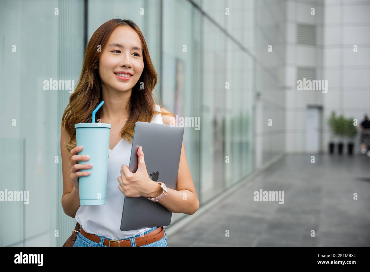 female entrepreneur with laptop and tumbler mug water multitasking ...