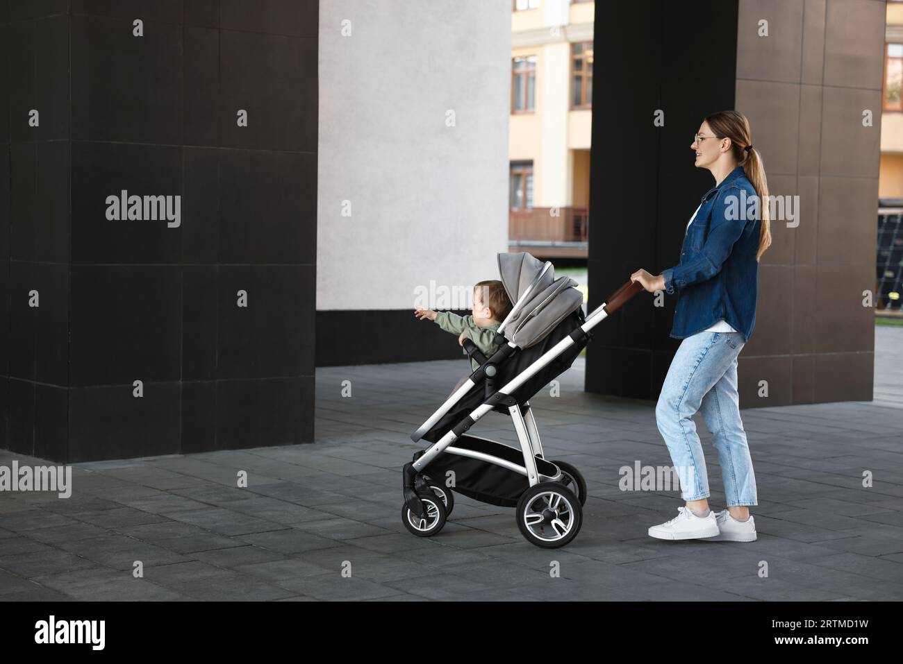 Beautiful nanny with cute little boy in stroller walking outdoors Stock ...