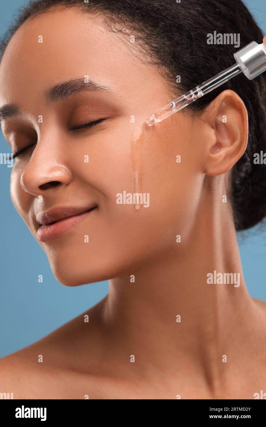 Beautiful woman applying serum onto her face, closeup Stock Photo - Alamy