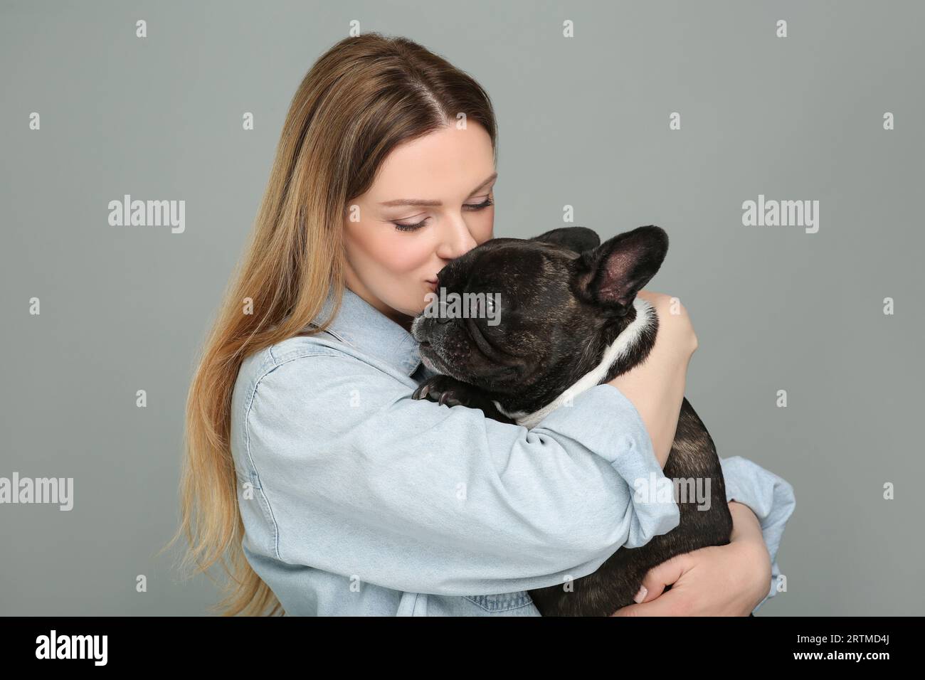 Woman hugging cute French Bulldog on grey background Stock Photo - Alamy
