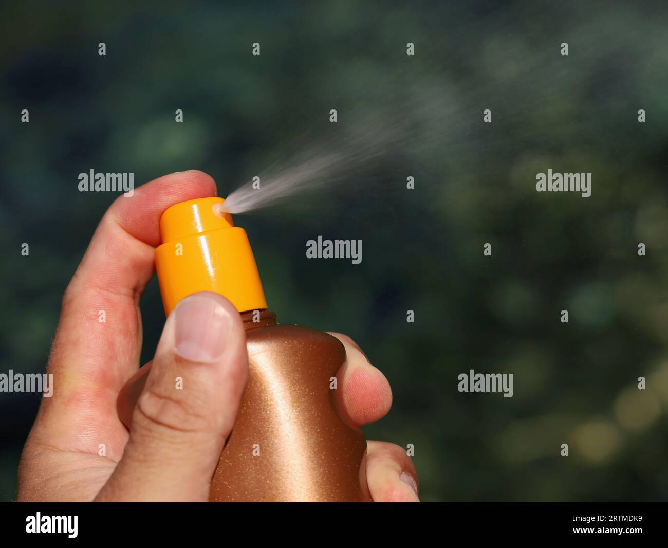 Using a spray bottle with sunscreen cream on the beach, concept of skin ...
