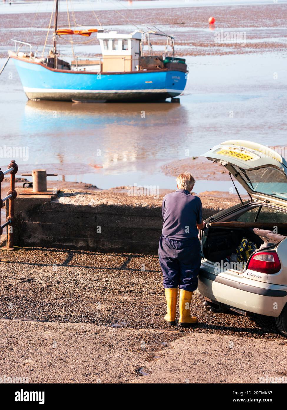 older man in yellow welly's getting ready to board fishing boat near ...