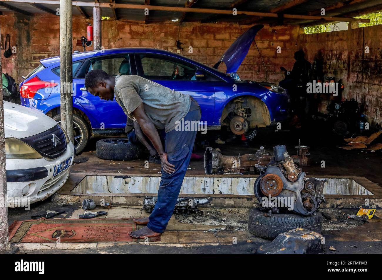 Muslim mechanic praying in the garage where he works in Fatick ...