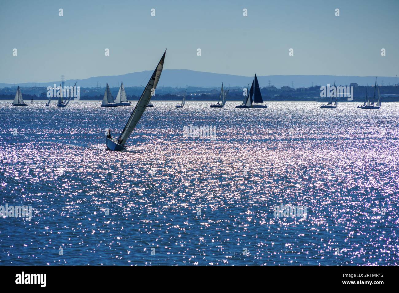 yachts on the shimmering blue water of a river lake sailing together ...