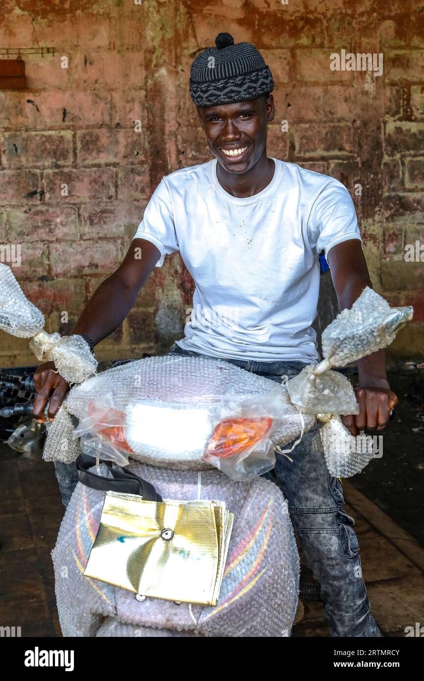 Smiling young Senegalese sitting on a new wrapped scooter in Fatick ...