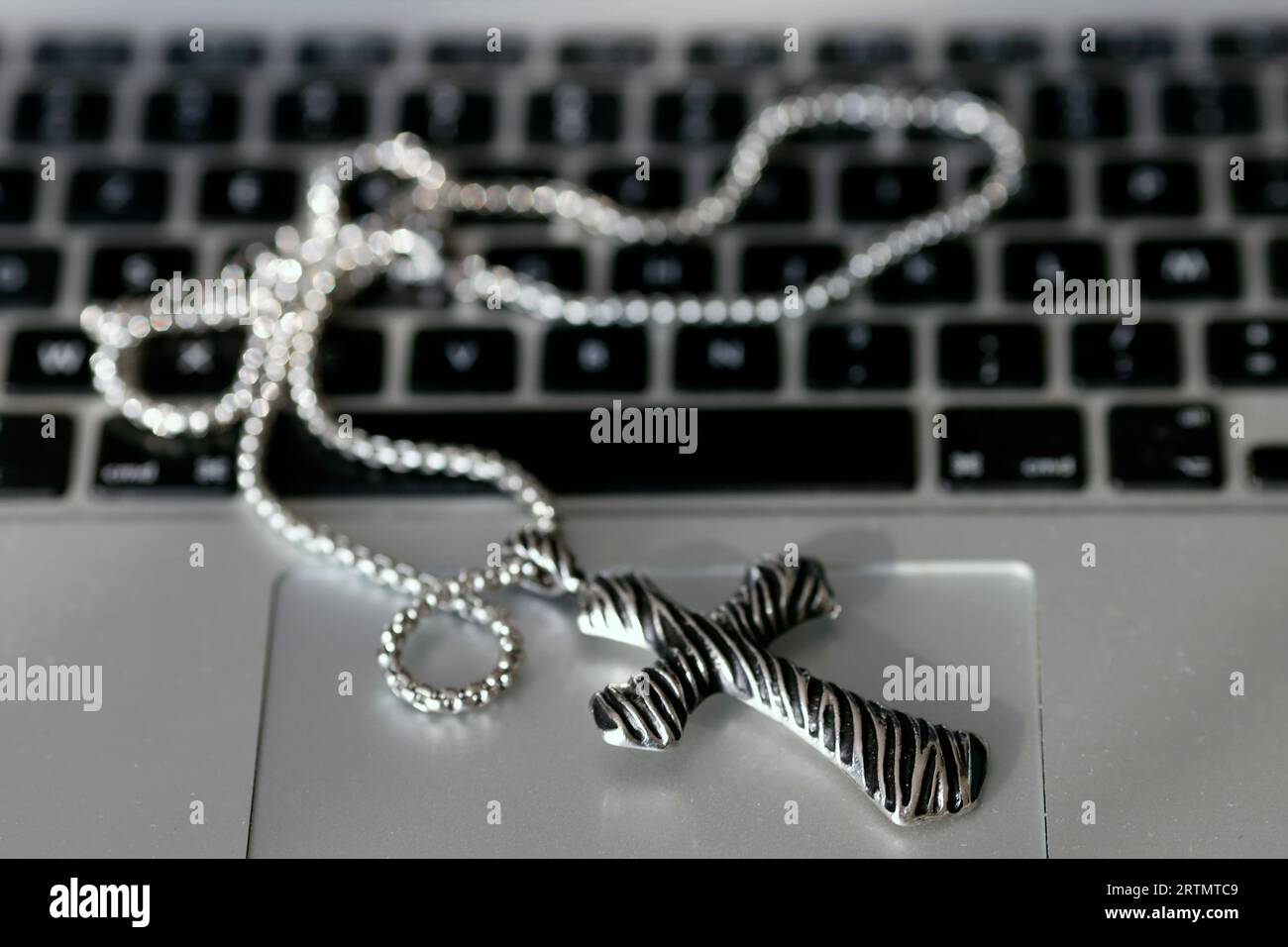 Silver christianity cross pendant on a laptop. Religious and digital ...