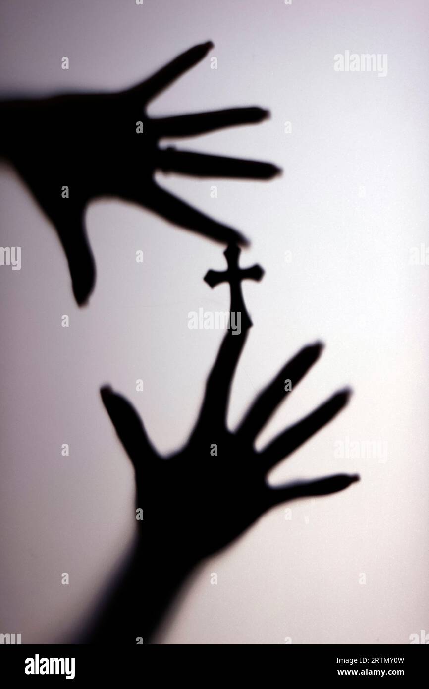 Silhouette of hands showing a catholic cross on white background ...