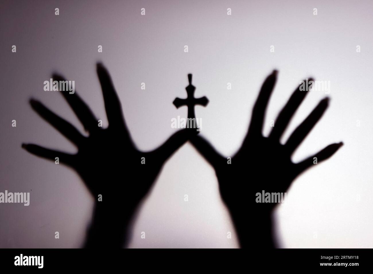 Silhouette of hands showing a catholic cross on white background ...