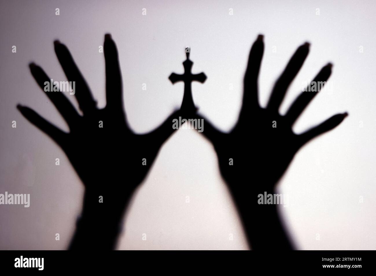 Silhouette of hands showing a catholic cross on white background ...