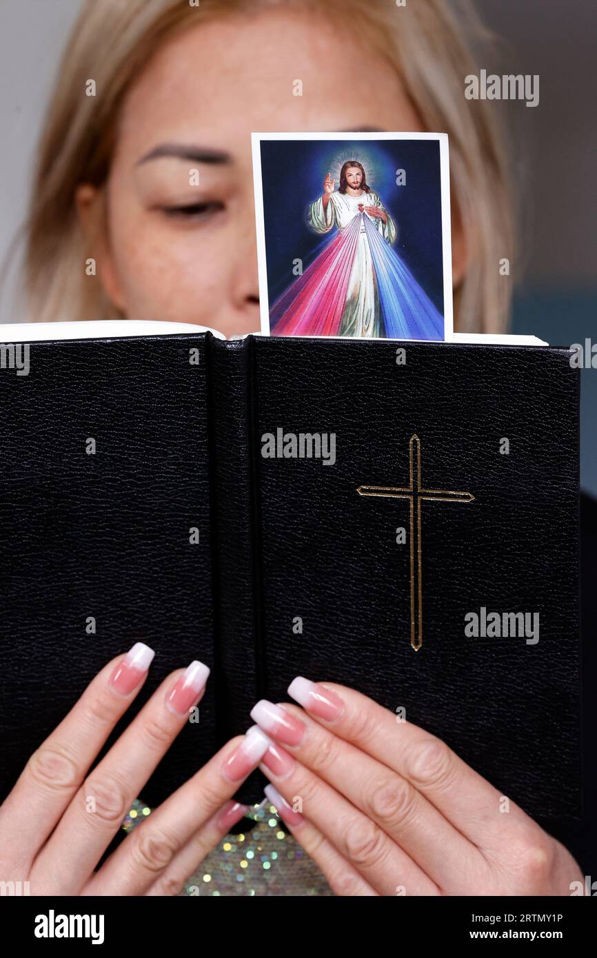 Catholic woman reading the bible with an image of Jesus. Faith concept ...