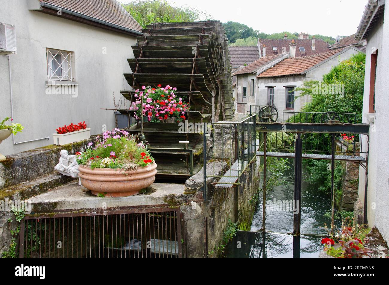 Rustic Wooden Waterwheel next to baskets of flowers with river flowing ...