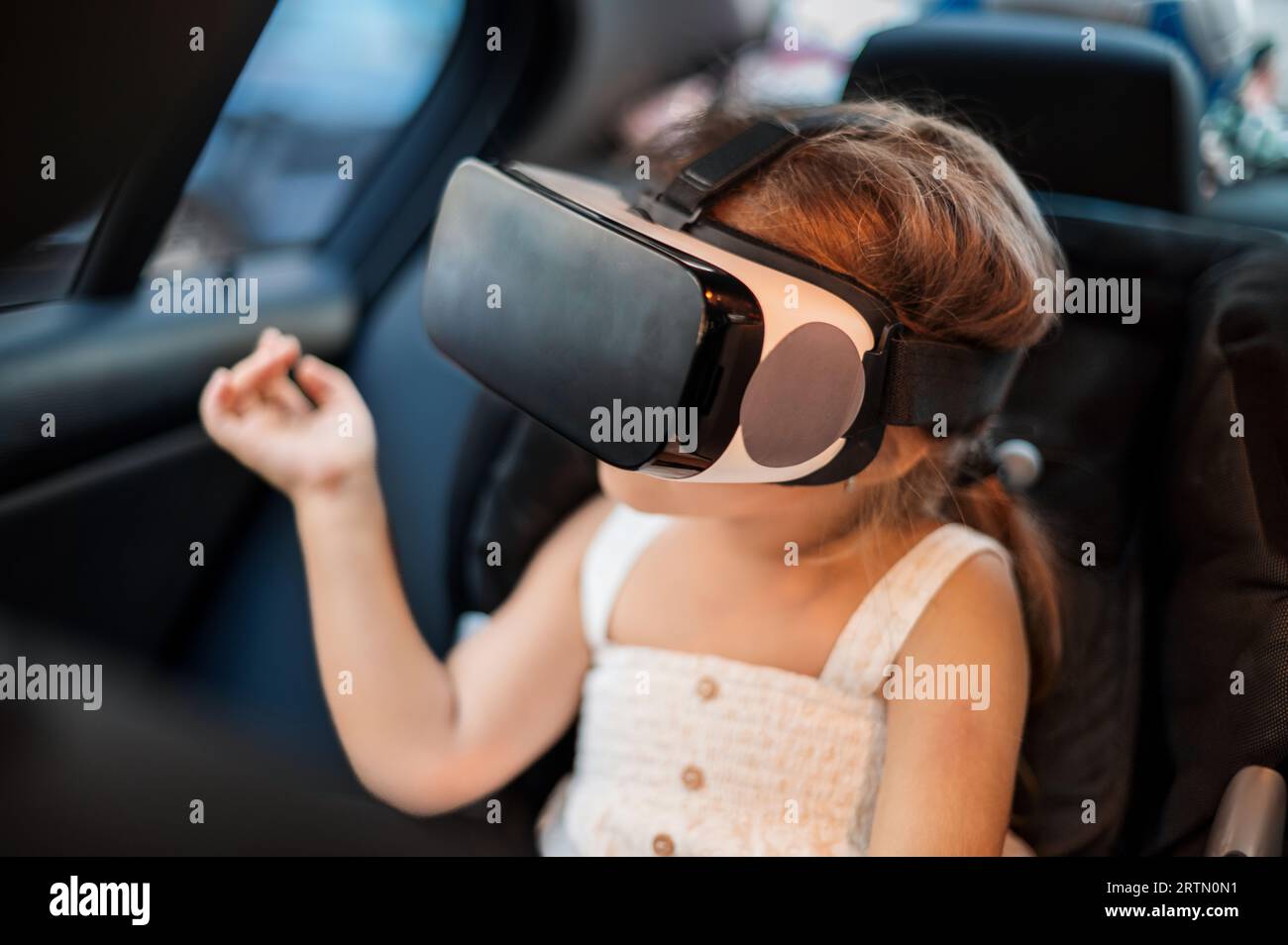 Small girl sitting in the car in VR glasses in child safety seat Stock ...