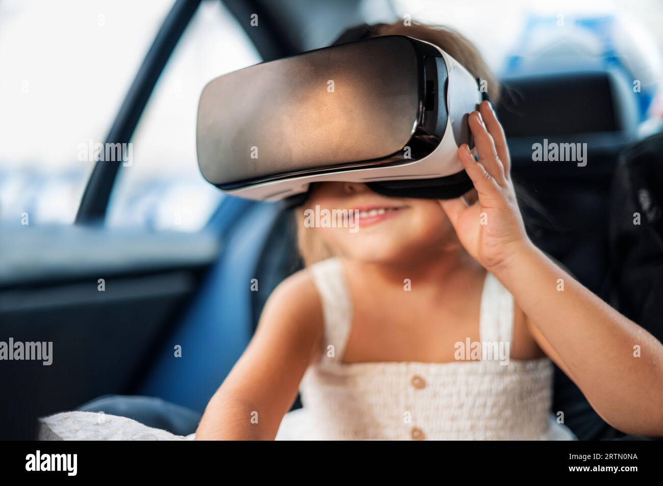 Small girl sitting in the car in VR glasses in child safety seat Stock ...